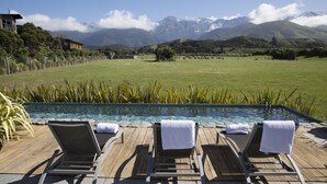Área da piscina com espreguiçadeiras e vista para as montanhas.