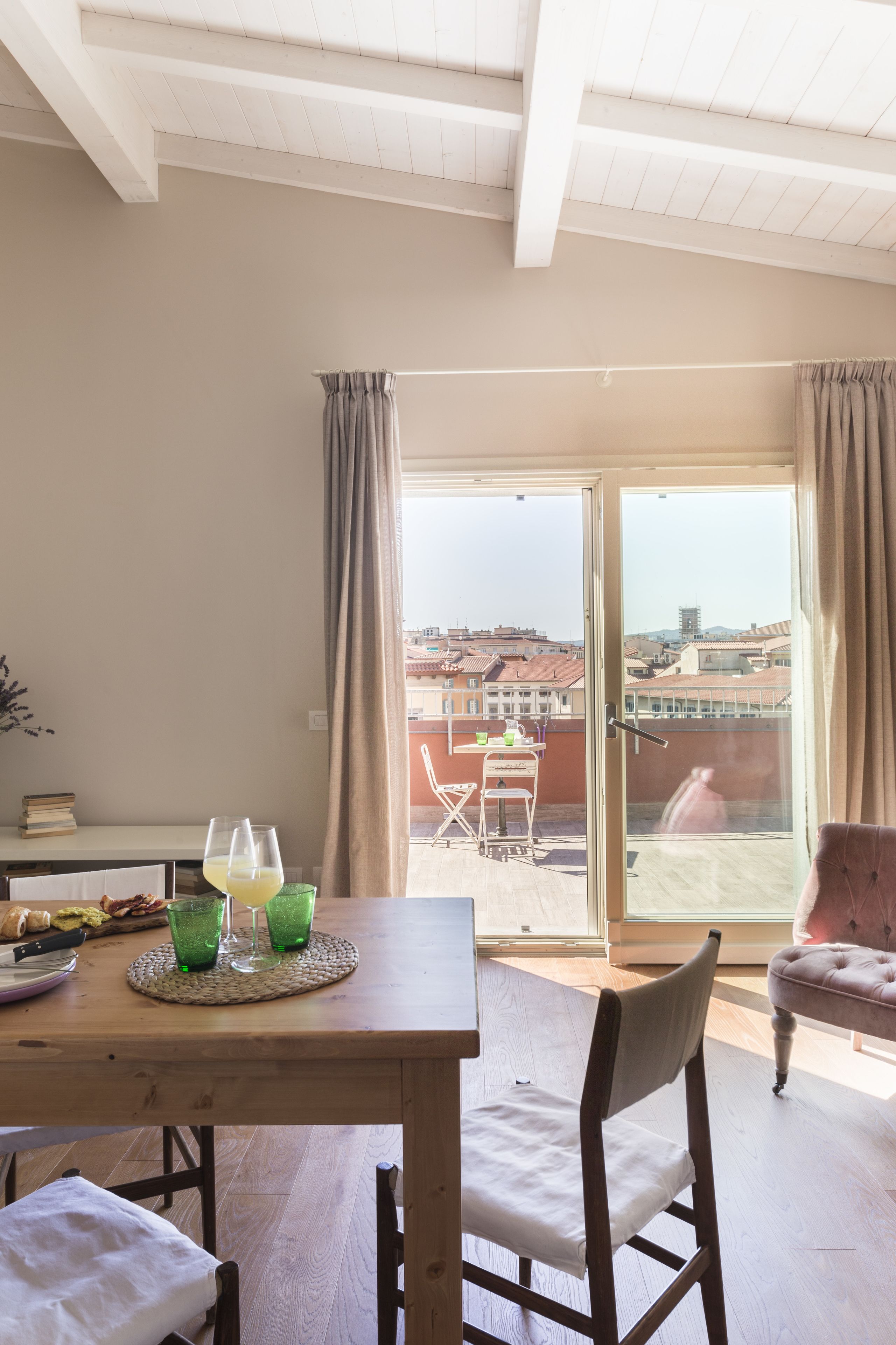 Uma sala de jantar com mesa, cadeiras e vista para a cidade através de uma porta de vidro.