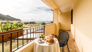 Varanda com mesa posta para o café da manhã, com vista para a paisagem costeira.