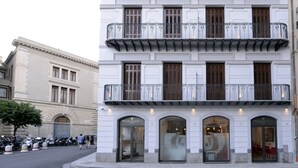 Um edifício com vários andares, varandas, portas em arco e uma placa indicando que é um hotel.