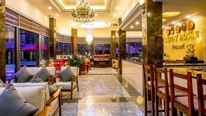 Um saguão com um lustre imponente, um piano e uma mesa de recepção.