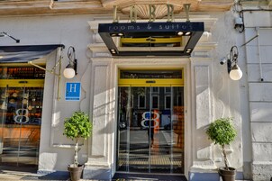 Entrada de hotel com placa indicando "rooms & suites" e sinal de acessibilidade para deficientes.
