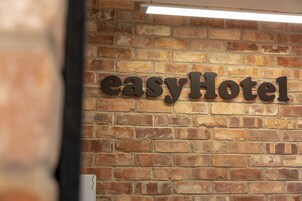 Paredes de tijolo com a inscrição 'easyHotel' em letras grandes e escuras.