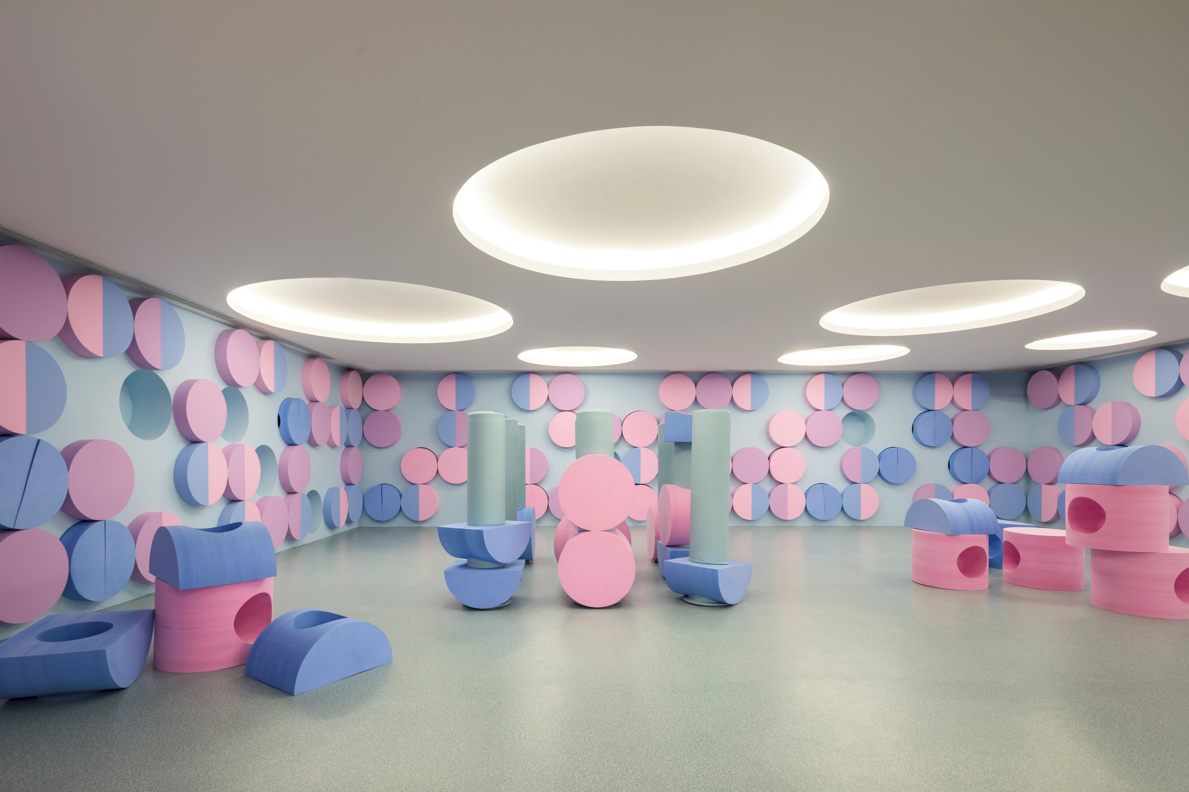 Um interior moderno com luminárias circulares no teto, parede estampada e móveis geométricos.