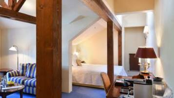Quarto de hotel com cama, sofá, escrivaninha e luminária.