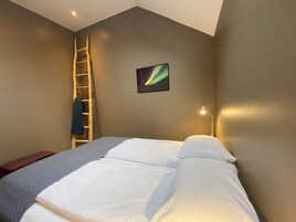 Quarto com cama, escada, quadro na parede e abajur.
