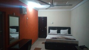 Quarto com cama, penteadeira, espelho e ventilador de teto.