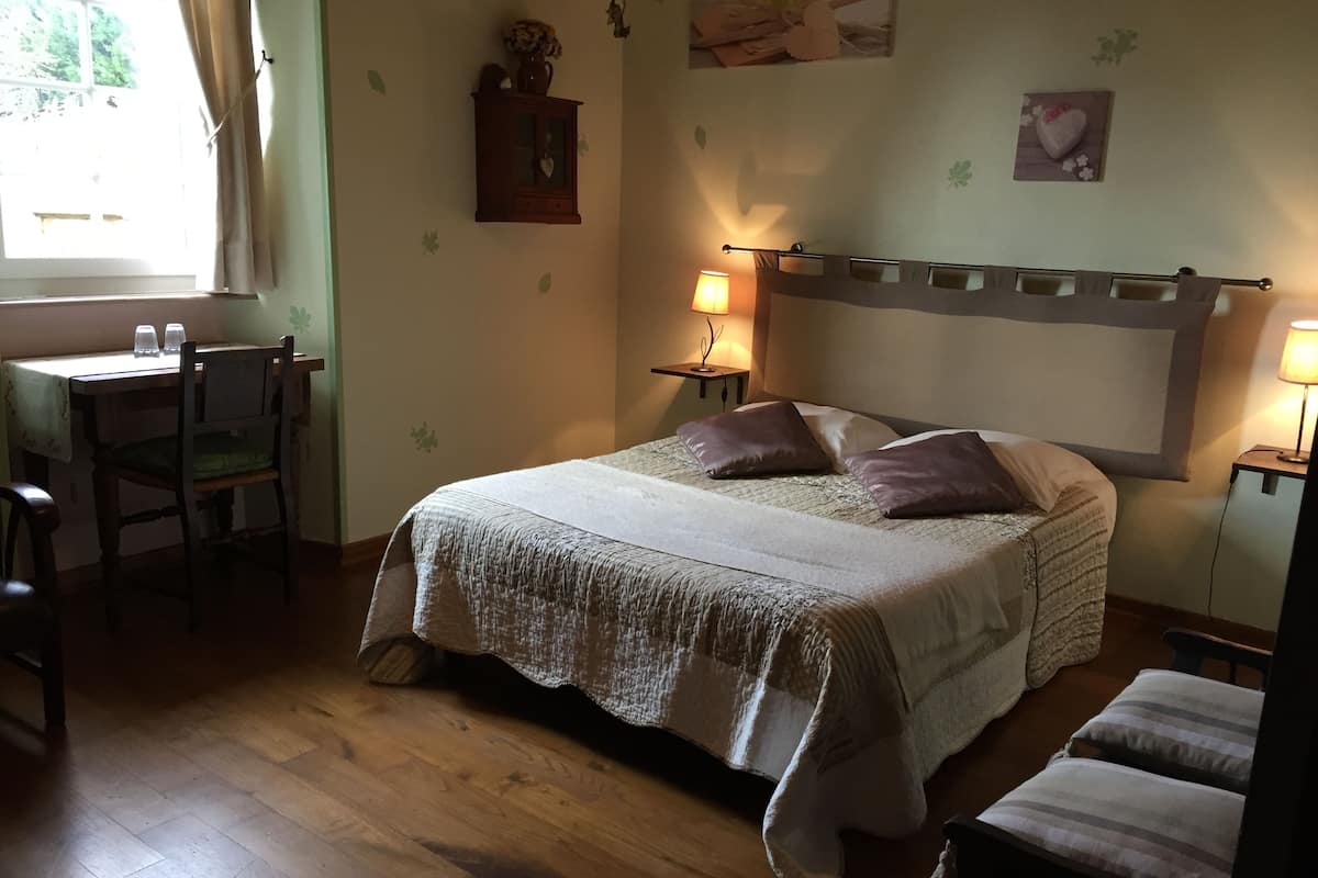 Quarto com cama, mesas de cabeceira, escrivaninha e uma cadeira.