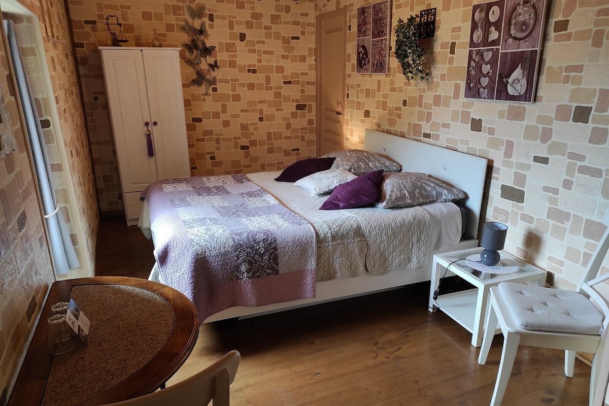Um quarto com cama, mesa de cabeceira, cadeira, mesa de madeira e guarda-roupa.