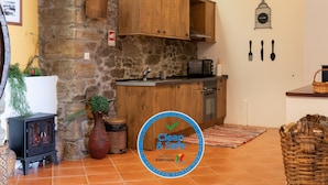 Cozinha com paredes de pedra, armários de madeira, fogão e um aviso indicando 'Clean & Safe' com um sinal de verificação.