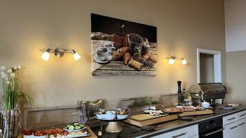 Buffet com diversos alimentos, um canto de café e um painel decorativo.