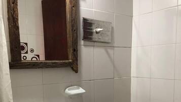 Casa de banho com lavatório branco, espelho e sanita.