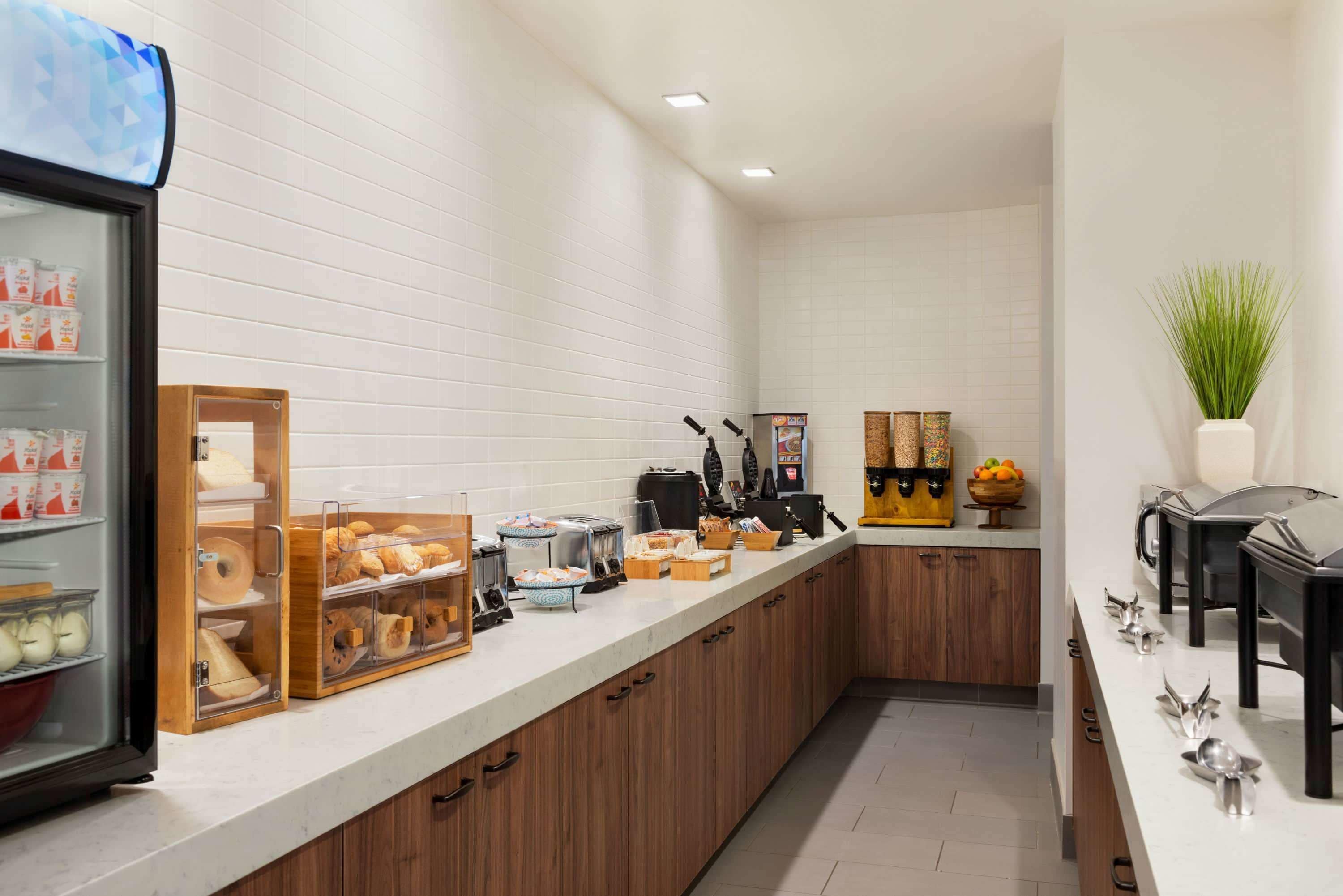 Um balcão de café da manhã limpo e moderno, com diversas opções de alimentos e uma estação de café.