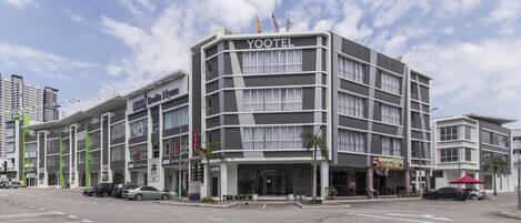 Um hotel moderno com um letreiro chamativo 'YOTEL', vários andares e vista para a rua com carros estacionados.