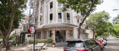 Hotel com fachada curva, placa de identificação e área de estacionamento com carros.