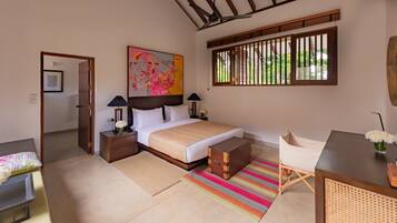 Quarto com cama, mesas de cabeceira, escrivaninha, janela com grades e um tapete colorido.