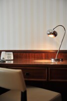 Uma mesa de madeira com um telefone e uma luminária.