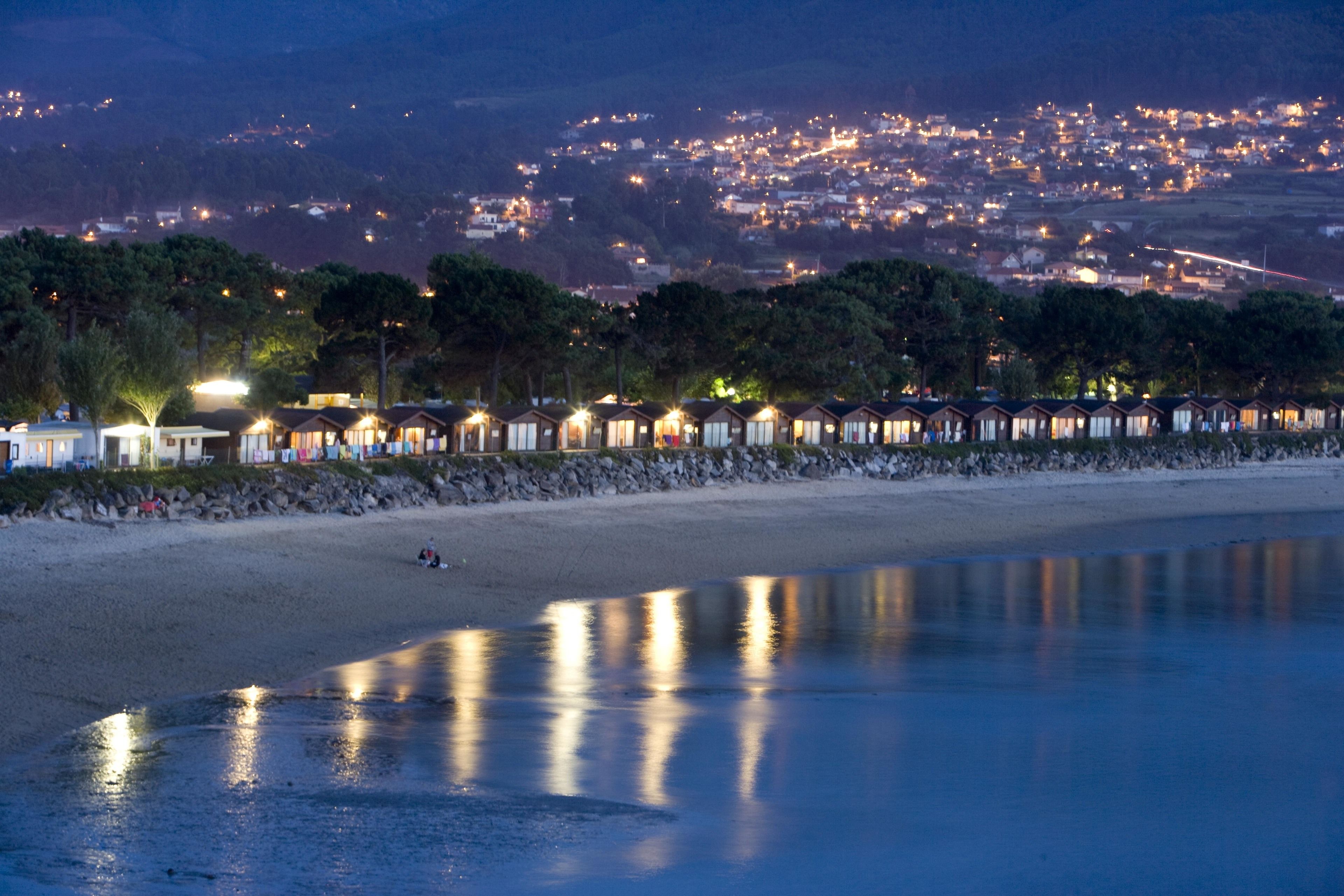 Uma praia com casas em fila e a faixa de areia em primeiro plano.