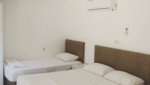 Quarto de hotel com duas camas, um ar condicionado branco e design simples e limpo.
