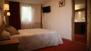 Quarto com cama, televisão fixada na parede e porta de madeira que dá para outro cômodo.