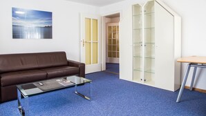 Uma sala de estar moderna com um sofá de couro marrom, uma mesa de centro de vidro e um tapete azul.