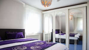 Quarto moderno com uma cama grande, guarda-roupa com espelhos e um candelabro.