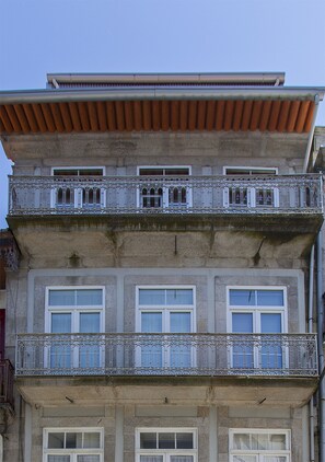 Um edifício com vários andares, varandas, janelas amplas e telhado plano.