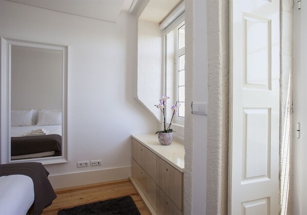Quarto com cama, janela com vista, penteadeira e porta.
