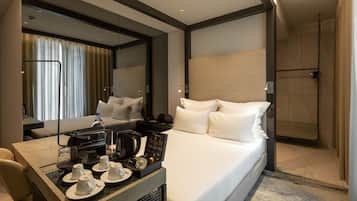 Quarto de hotel moderno com uma cama grande, uma escrivaninha com comodidades para café e chá, um espelho e zona de duche.
