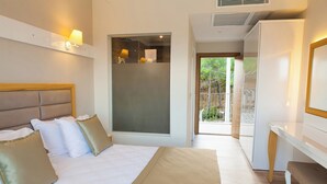 Quarto de hotel com cama, mesa de cabeceira e uma janela ampla.