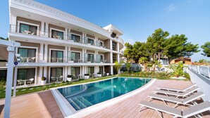 Um hotel com vários andares, piscina, área de estar externa e vegetação exuberante.