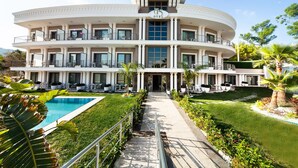 Um hotel com vários andares, piscina, área de estar externa e um jardim bem cuidado.