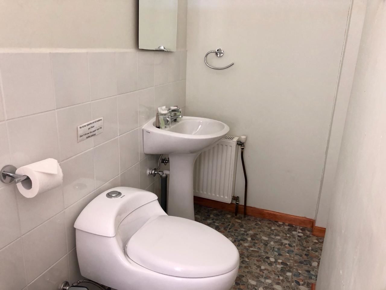 Um banheiro com vaso sanitário, pia e espelho.