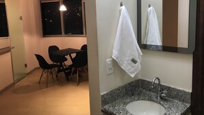 Um banheiro com uma pia de granito, um espelho e uma toalha branca pendurada na parede.