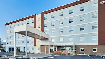 Um hotel com vários andares, entrada coberta e estacionamento.