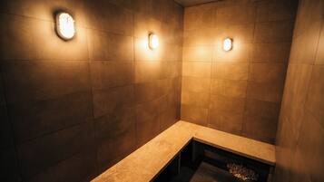 Um banheiro com paredes revestidas de azulejos, bancos e luminárias fixadas na parede.