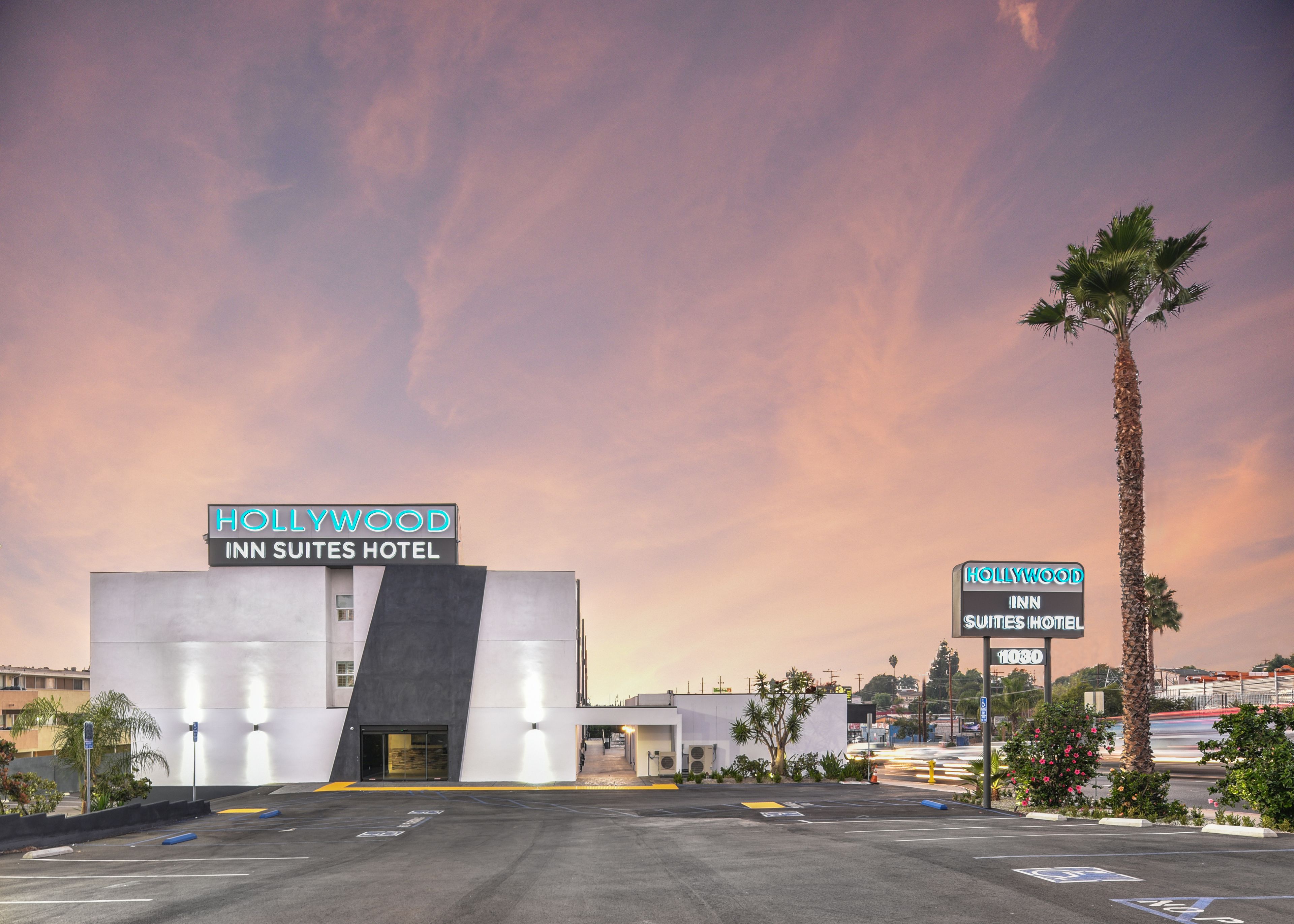 Hotel Hollywood Inn Suites, com design moderno, um estacionamento e céu claro.