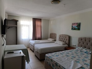 Quarto de hotel com duas camas, uma escrivaninha, televisão e uma janela com cortinas.