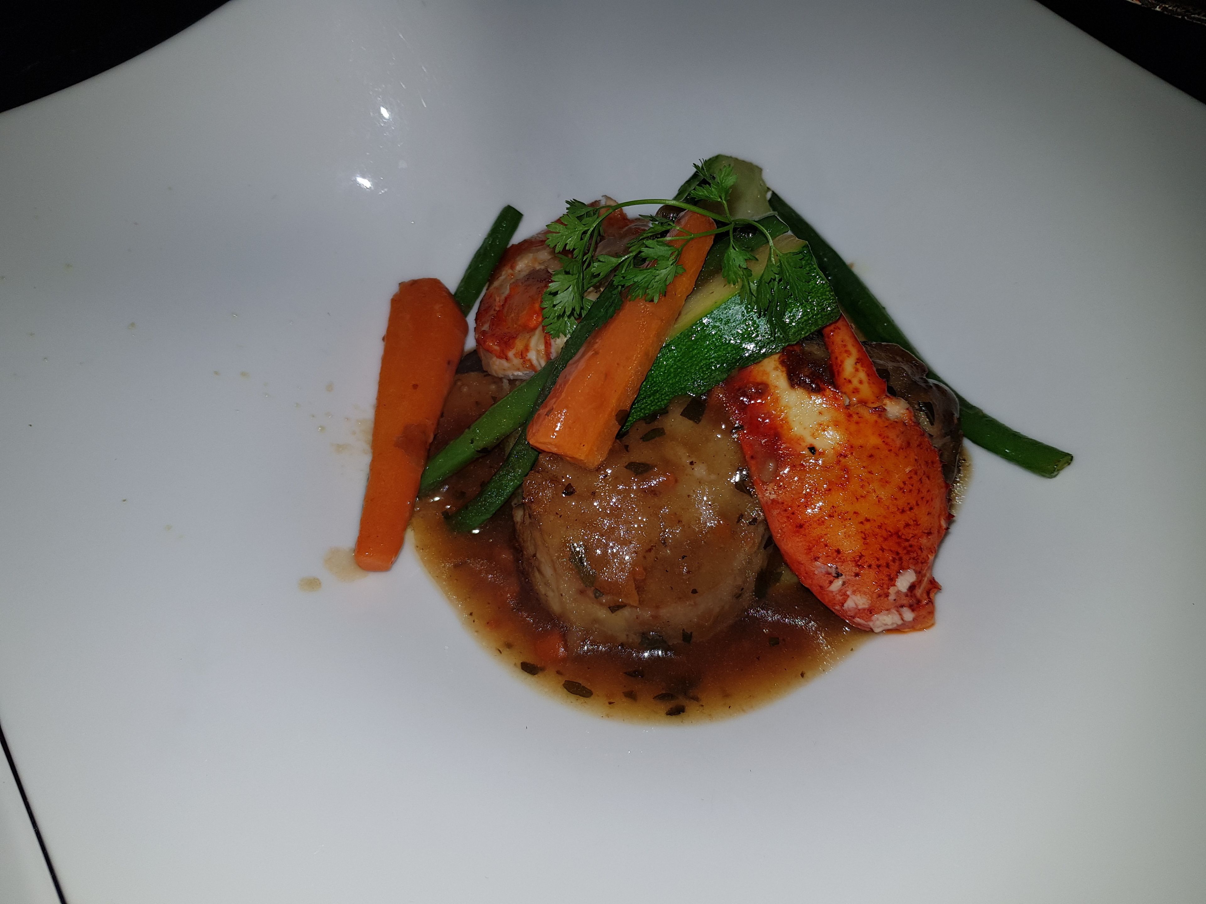 Um prato de comida com carne, cenouras e vegetais verdes.