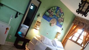 Quarto com duas camas, uma mesinha, um espelho e um ventilador fixado na parede.