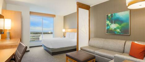 Quarto de hotel com cama, sofá, escrivaninha e cadeira.