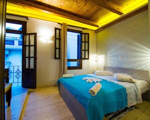 Quarto com teto de madeira, cama com colcha azul, duas almofadas brancas e uma toalha enrolada na cama.