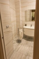 Um banheiro moderno com piso de mármore, pia branca e divisória de vidro.