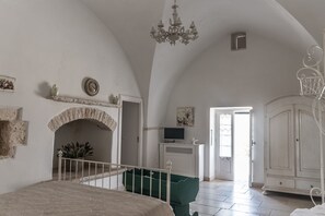 Quarto com lareira de pedra, cama, televisão e guarda-roupa.