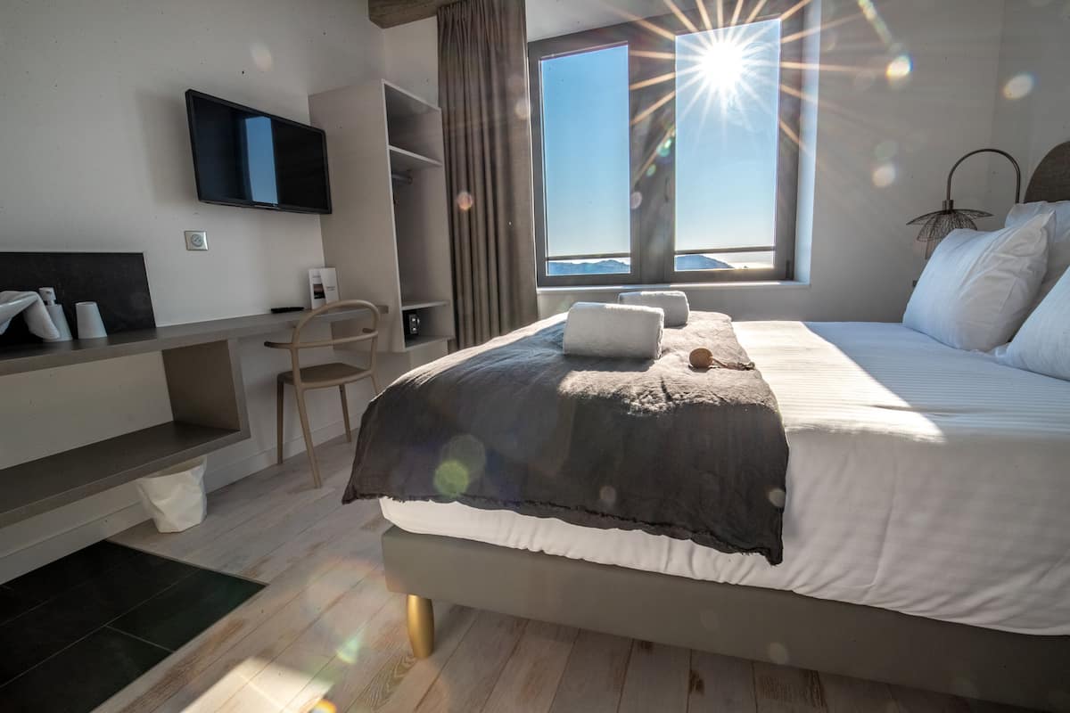 Quarto de hotel moderno com cama, televisão, escrivaninha e janela com vista.