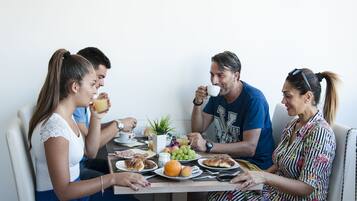 Um grupo de pessoas sentadas à volta de uma mesa com comida e bebidas.