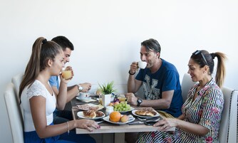 Um grupo de pessoas sentadas à volta de uma mesa com comida e bebidas.