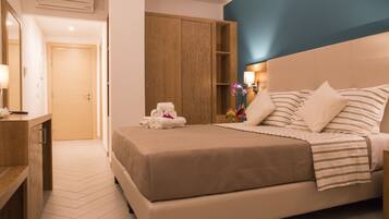 Quarto de hotel com uma cama, guarda-roupa, escrivaninha e espelho.