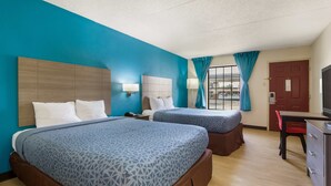 Quarto de hotel com duas camas, uma escrivaninha e uma televisão.
