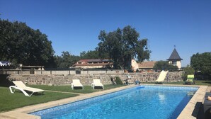 Piscina com espreguiçadeiras, hidromassagem e uma parede de pedra.
